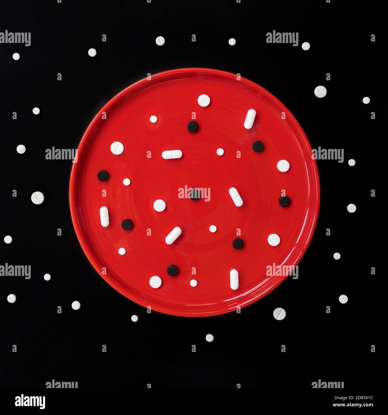 Red plate with of white and black pills, concept of correct use of ...
