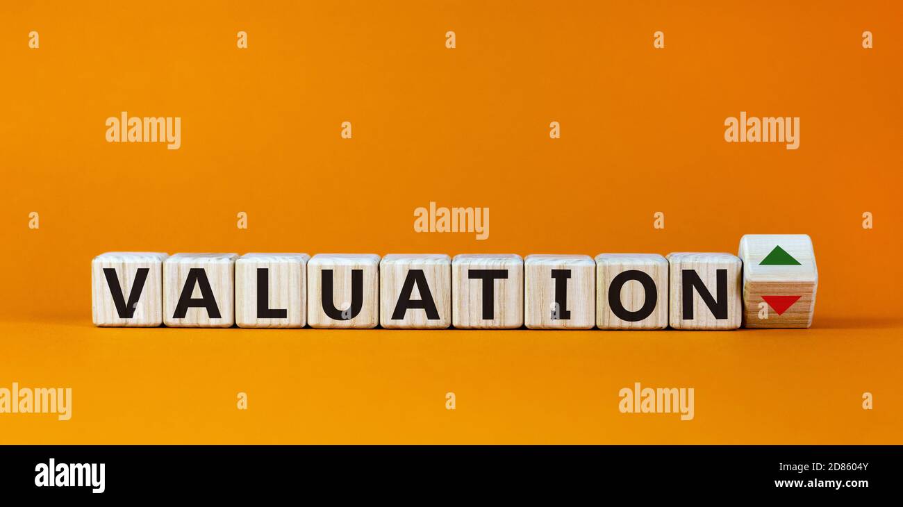 Valuation word on wooden cubes, up and down signs on orange background ...