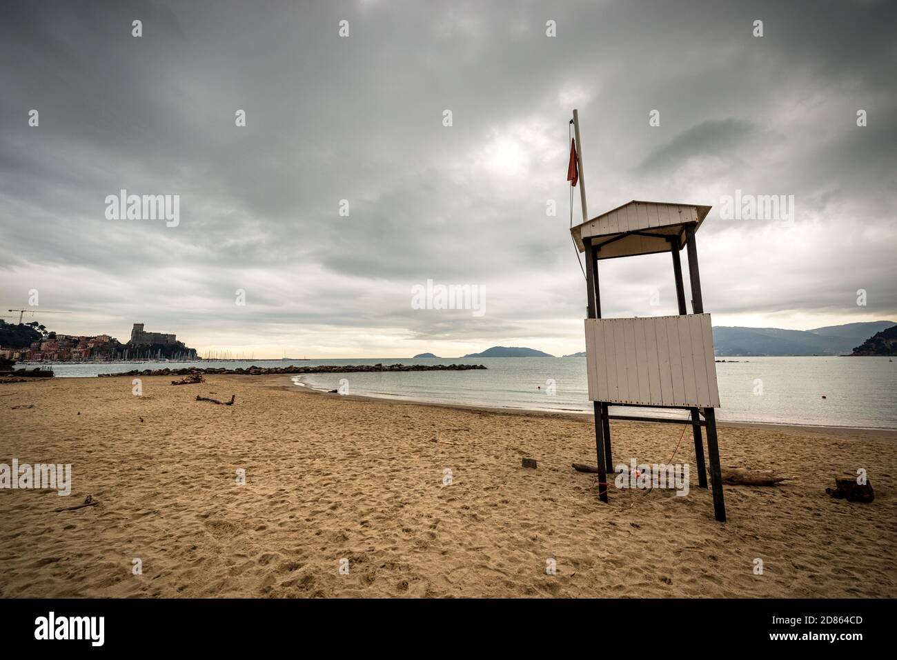 Empty beach with a lifeguard tower and red flag in winter, Lerici town ...