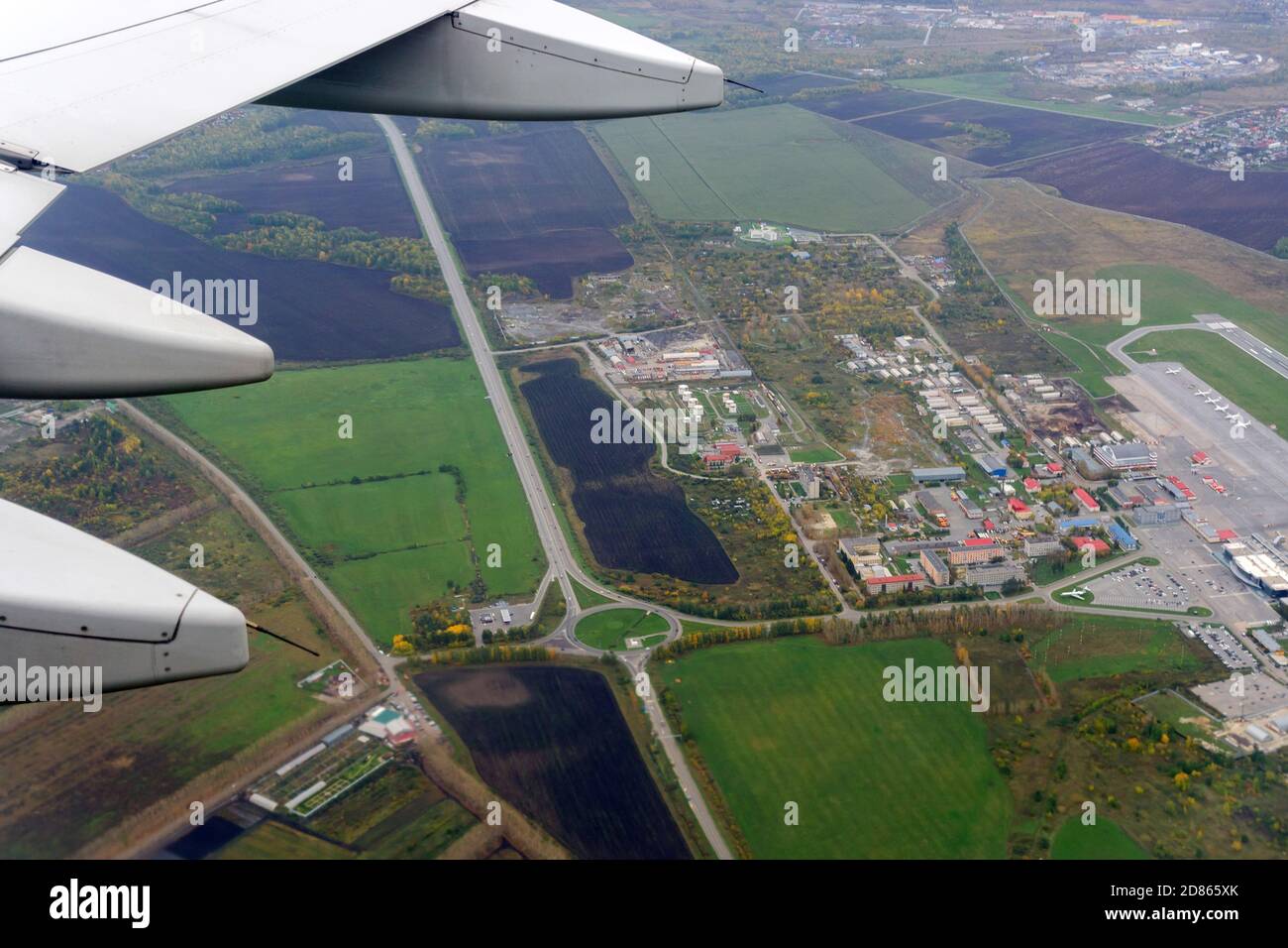 Airplane in the sky over fields the wing is visible through the window ...