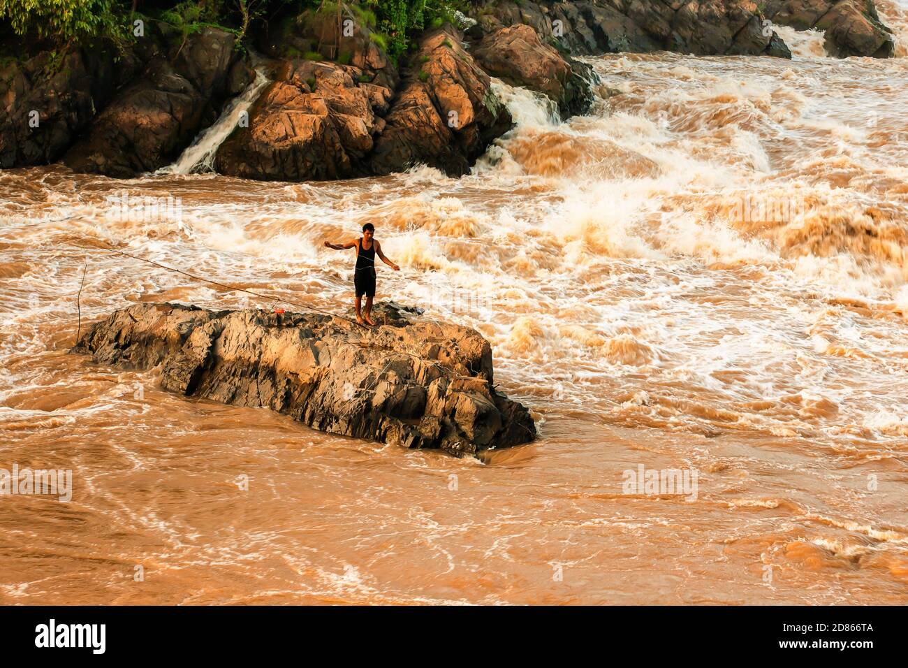 Champasak, Laos - OCTOBER 24, 2010: Laotian fisherman stands on the ...