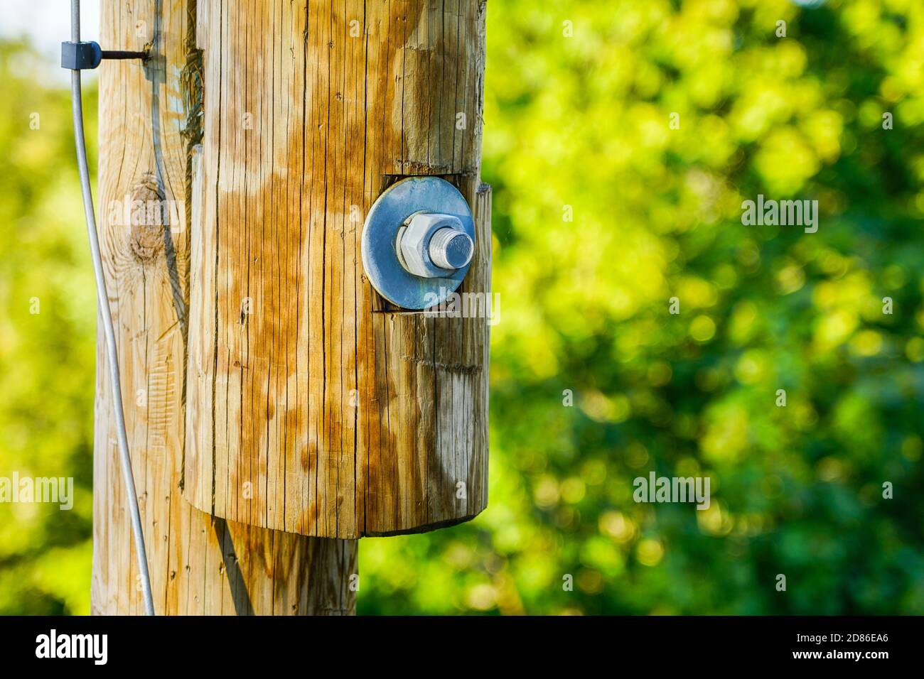 connecting a wooden round log structure with a metal screw on a green ...