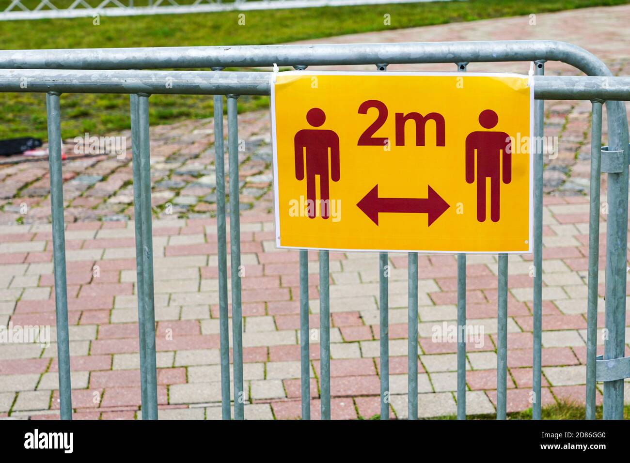 a metal barrier with a pictogram for keeping a distance of two meters ...