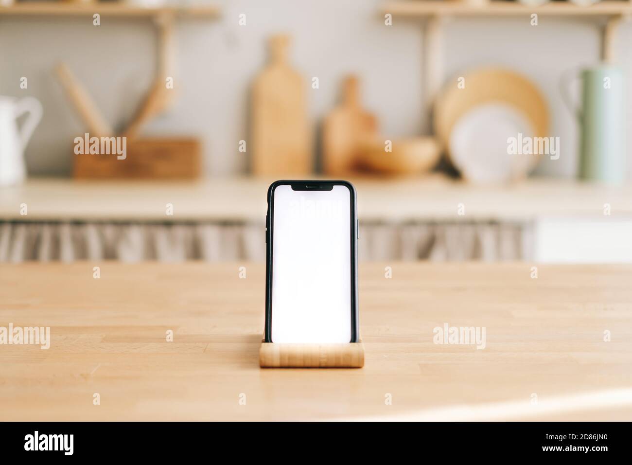 Smartphone with vertical white screen on the wooden table in kitchen ...