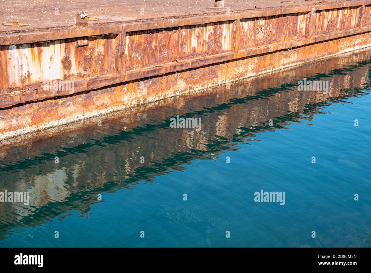 Rusty metal old industrial harbor quay reflections on the clear blue ...