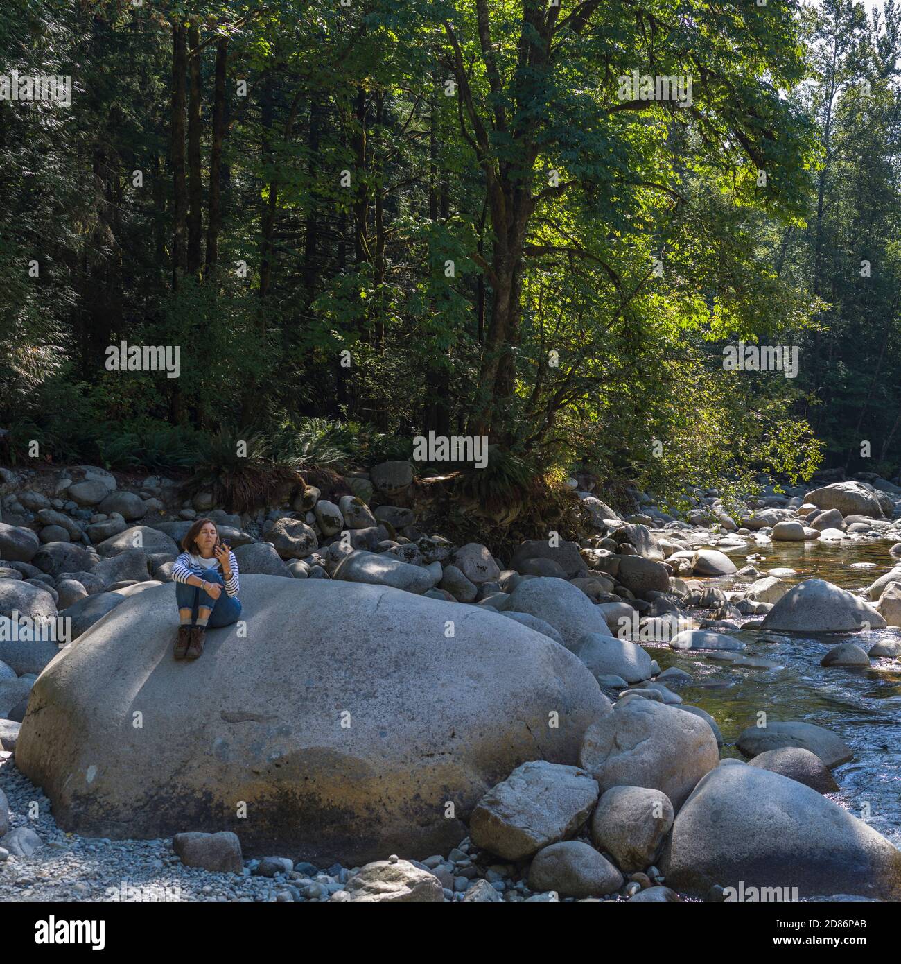 Woman sitting on rock, Lynn Canyon Park, Vancouver, Lower Mainland ...