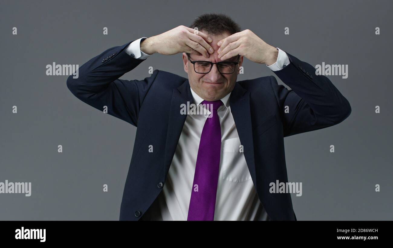 Tired and puzzled businessman suffers from headache rubbing forehead ...