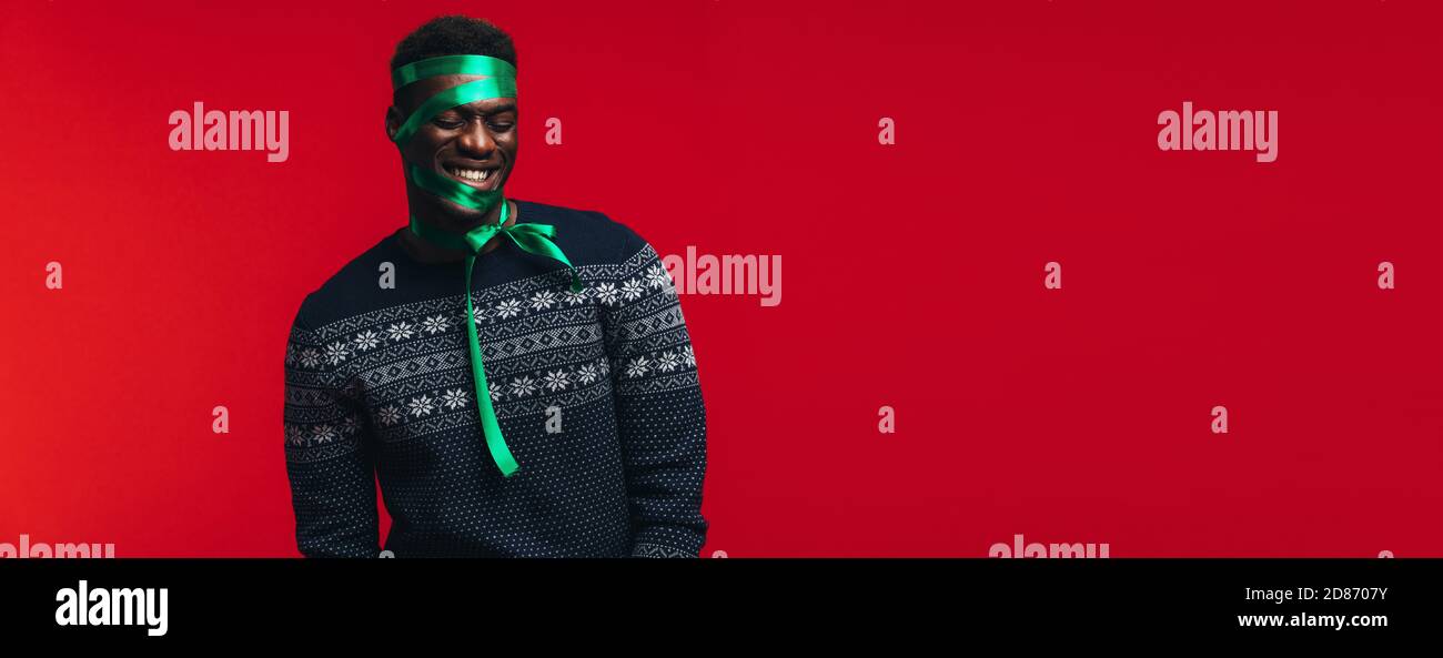 Happy african man with satin ribbon tied on his face against red ...
