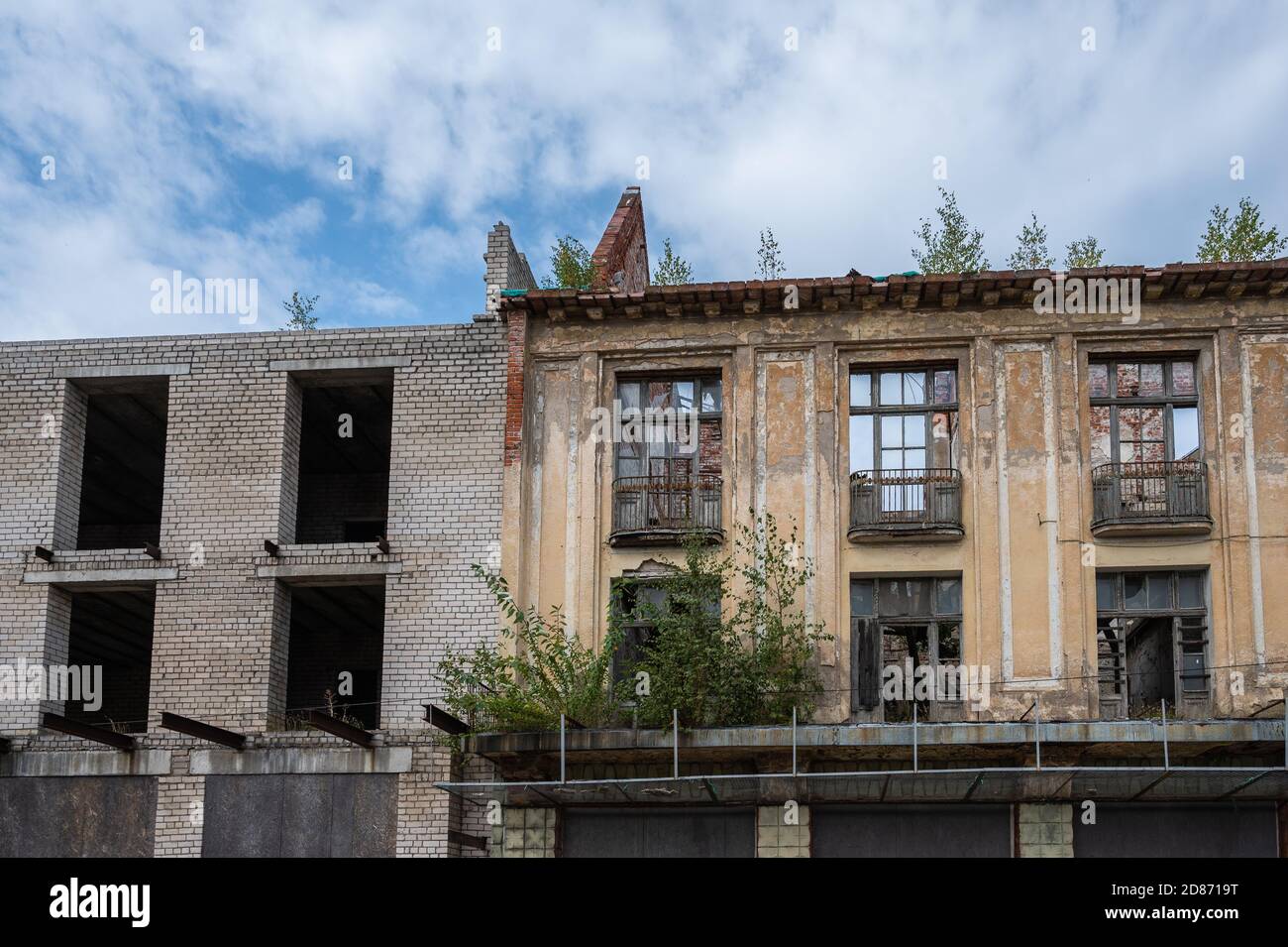 Facade of the old destroyed building with a brick extension against a ...