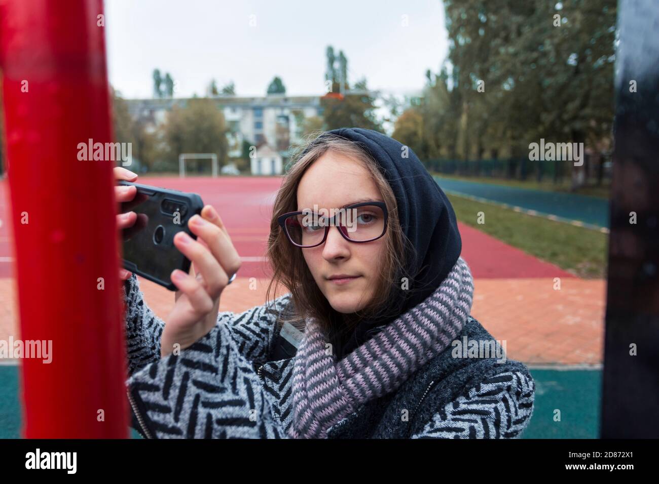 Beautiful girl takes pictures on smartphone on walk in spring or autumn ...