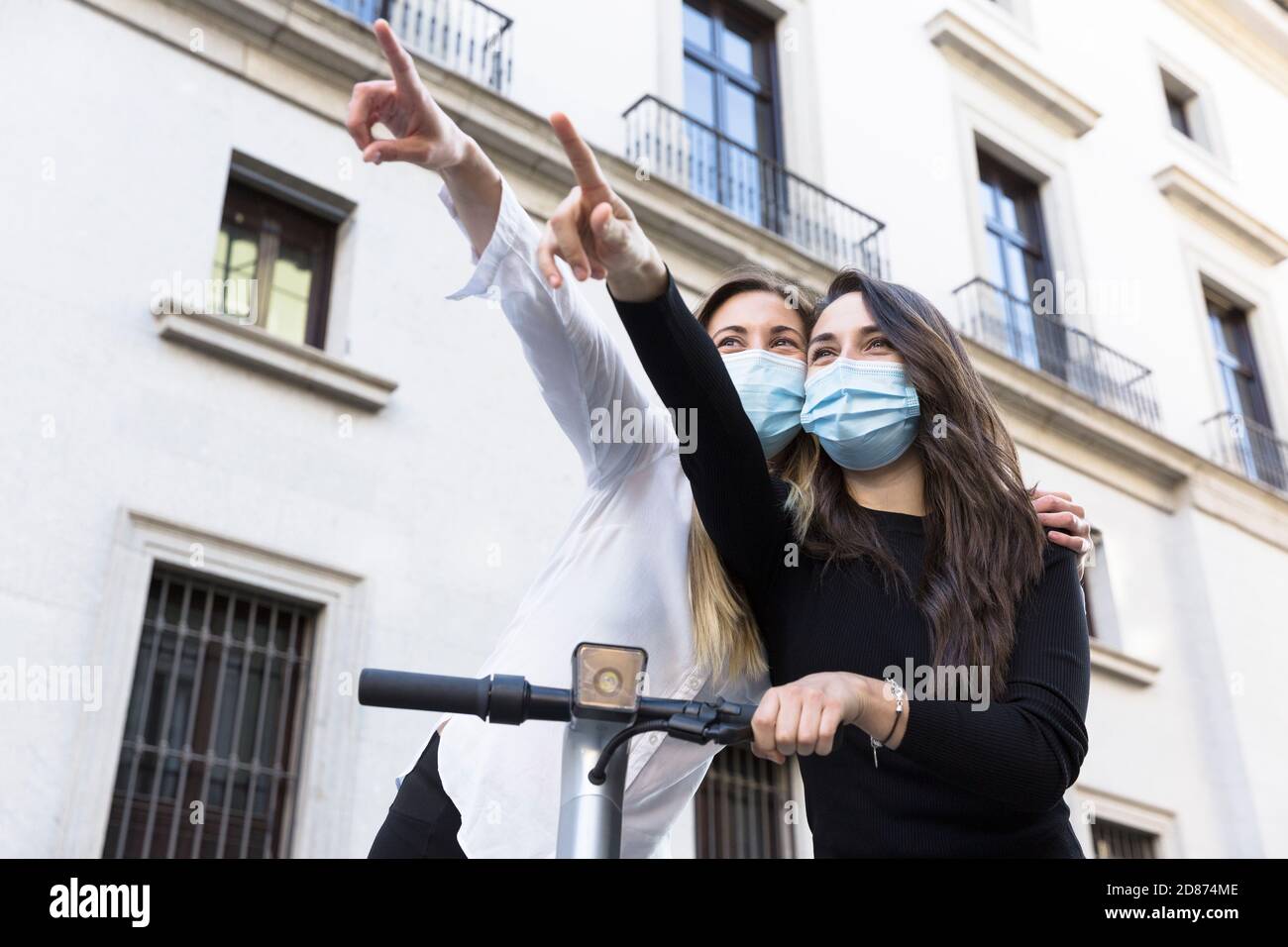 Two funny girls pointing their hands in one direction. They are ...