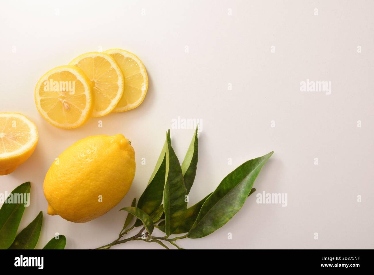 Background with cut and sliced organic lemon on a white table. Top view ...