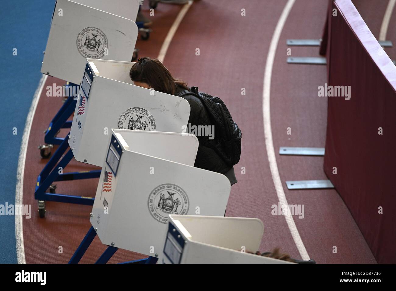 New York City, USA. 27th Oct, 2020. A womman stands behind a voter ...
