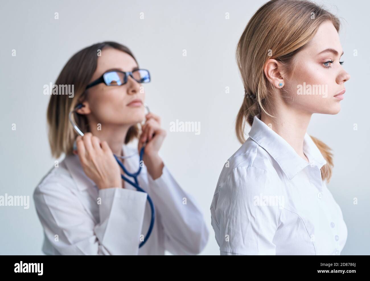 Professional doctor woman with stethoscope and female patient side view ...