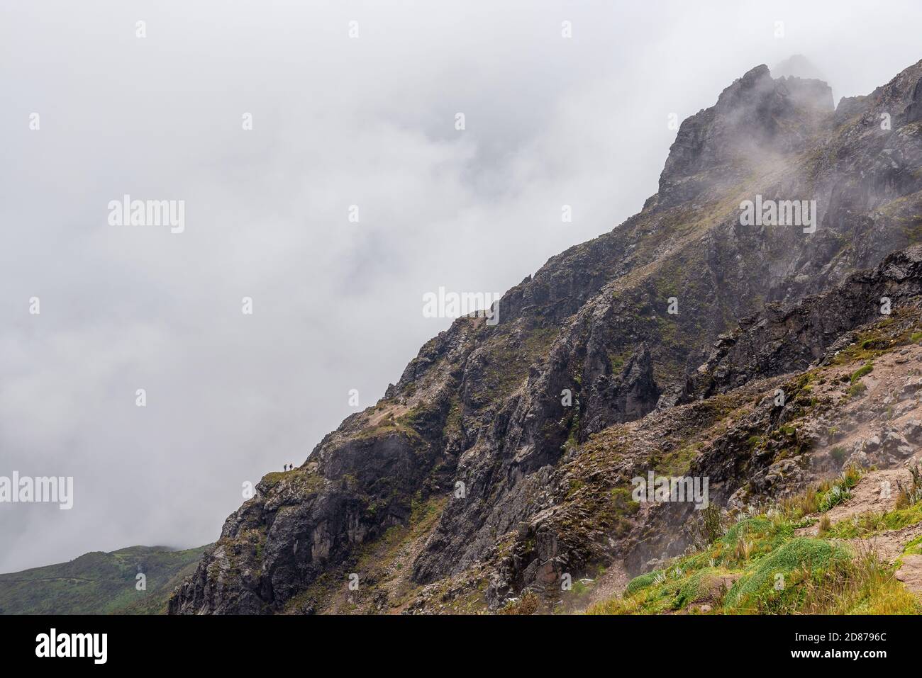 The silhouette of two people climbing the Rucu Pichincha volcano peak ...