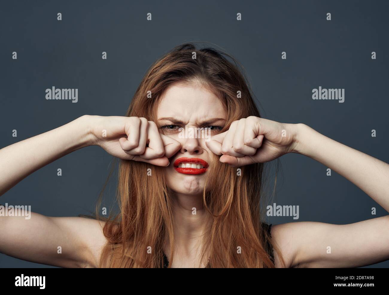woman with red lips crying on gray background and hands near face ...