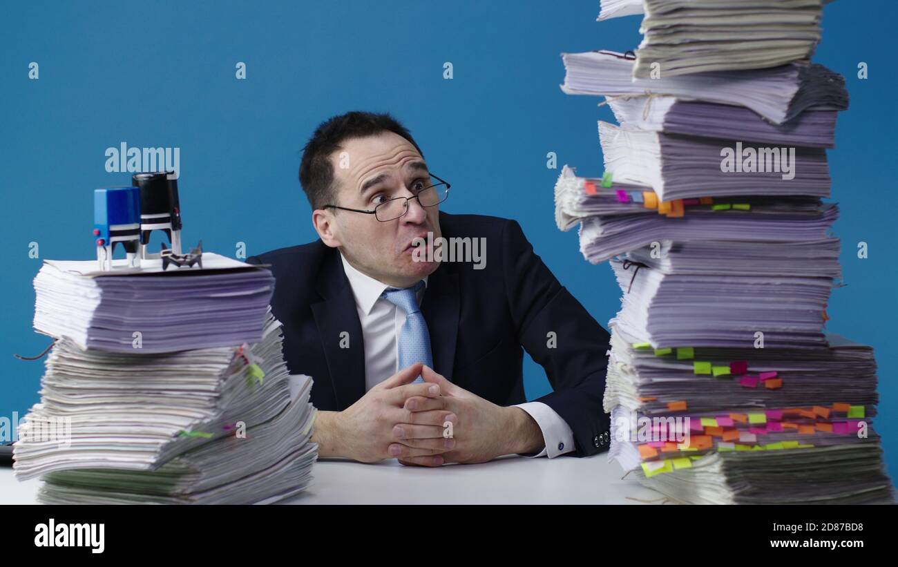 Office worker sits at desk looks on piles of paperwork with fear Stock ...