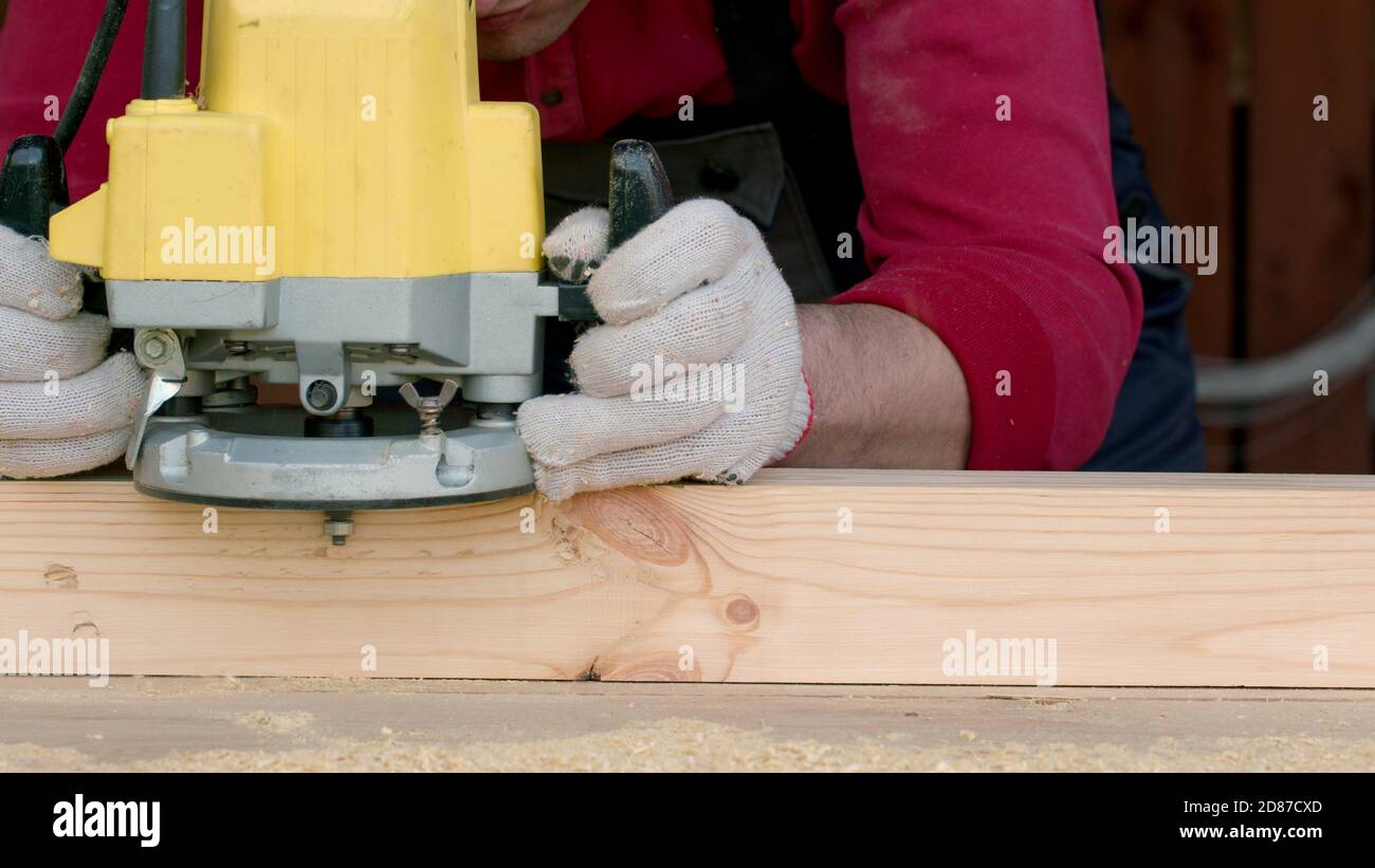 Csucasian carpenter processes wood beam with milling machine Stock ...
