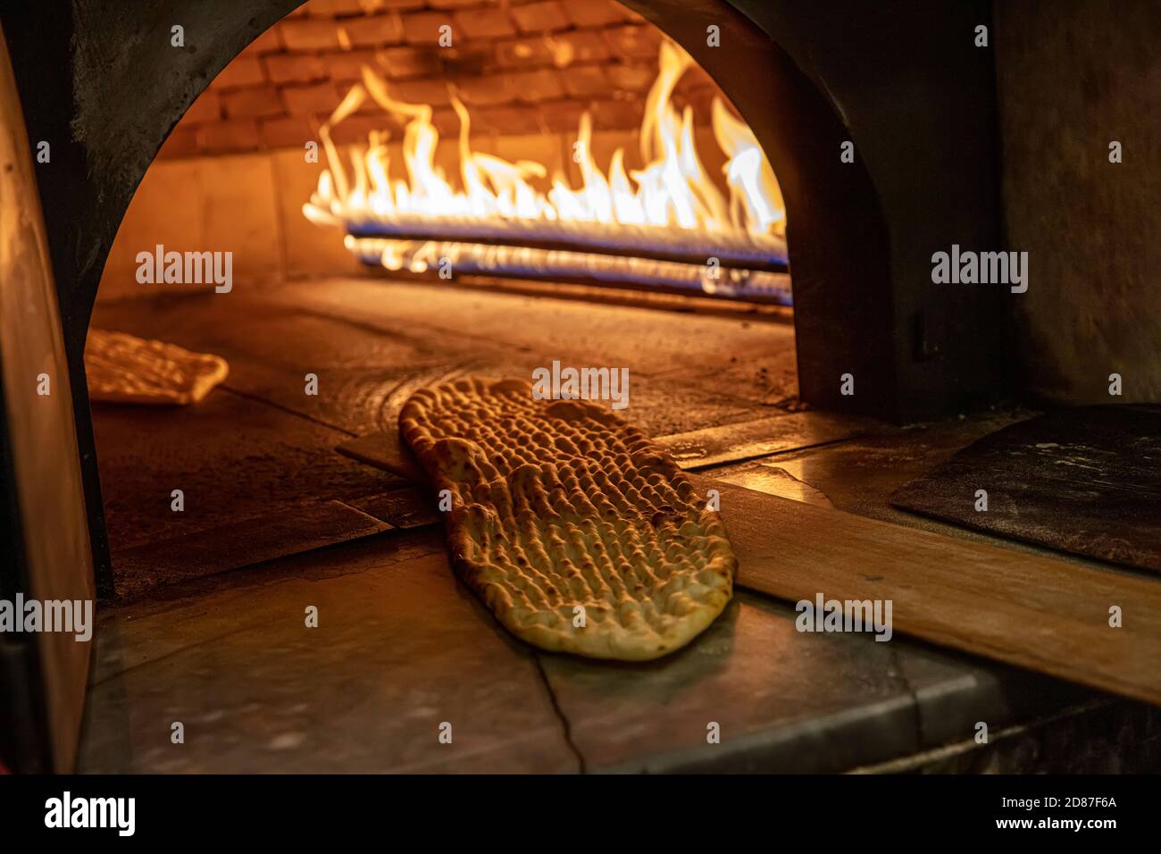 Turkish cuisine, pita bread in stone brick natural flame oven on wooden ...