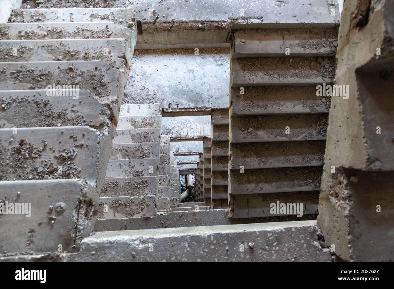 Dusty concrete staircase inside abandoned ruined building. Looking down ...