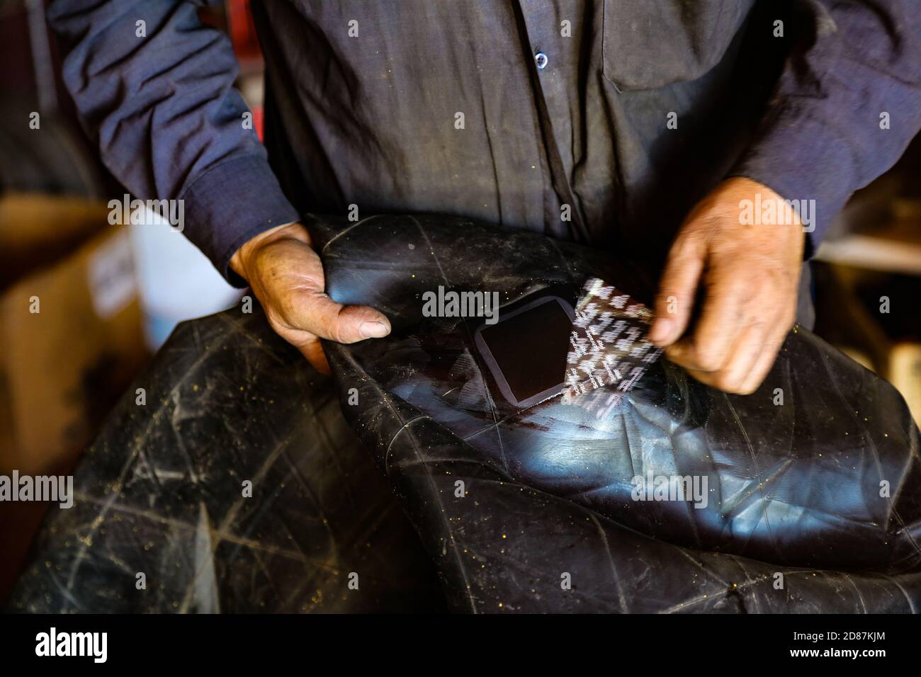 Man putting patch on tractor wheel inner tube Stock Photo - Alamy