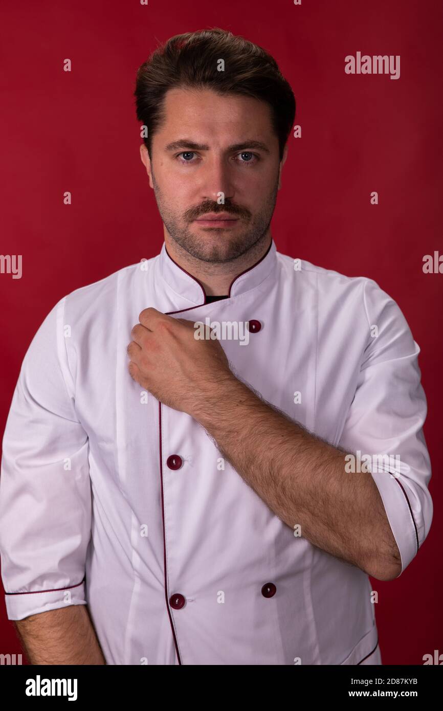 tired Unshaven handsome chef takes off uniform after long shift on red ...