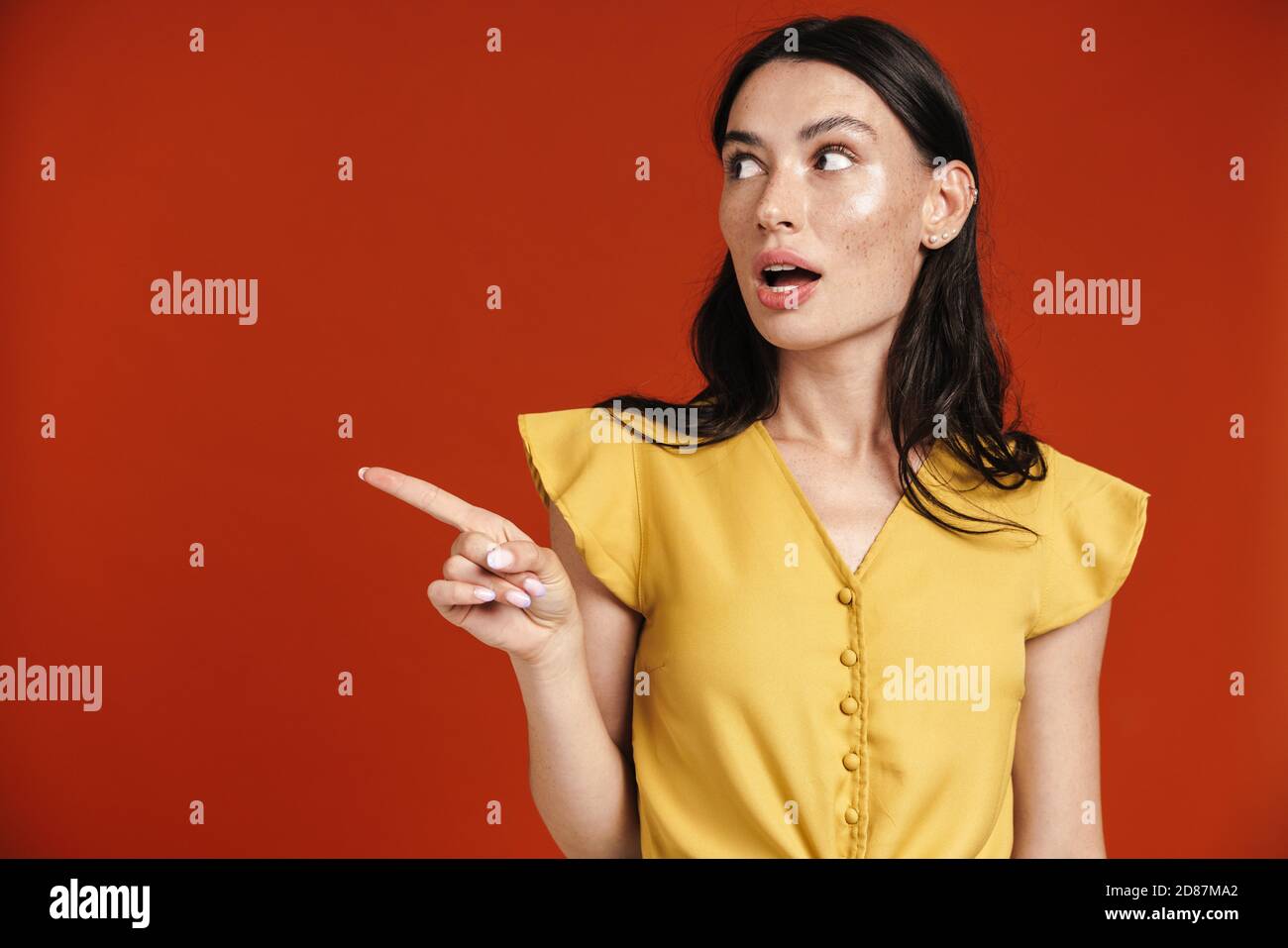 Image of young surprised woman pointing finger and looking aside ...