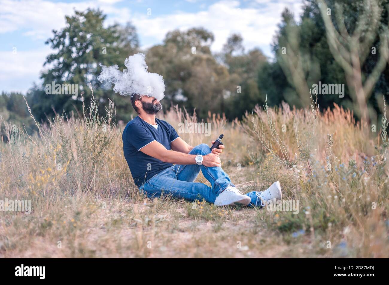 Modern smoker in the fresh air smoking an electronic cigarette. Vape ...