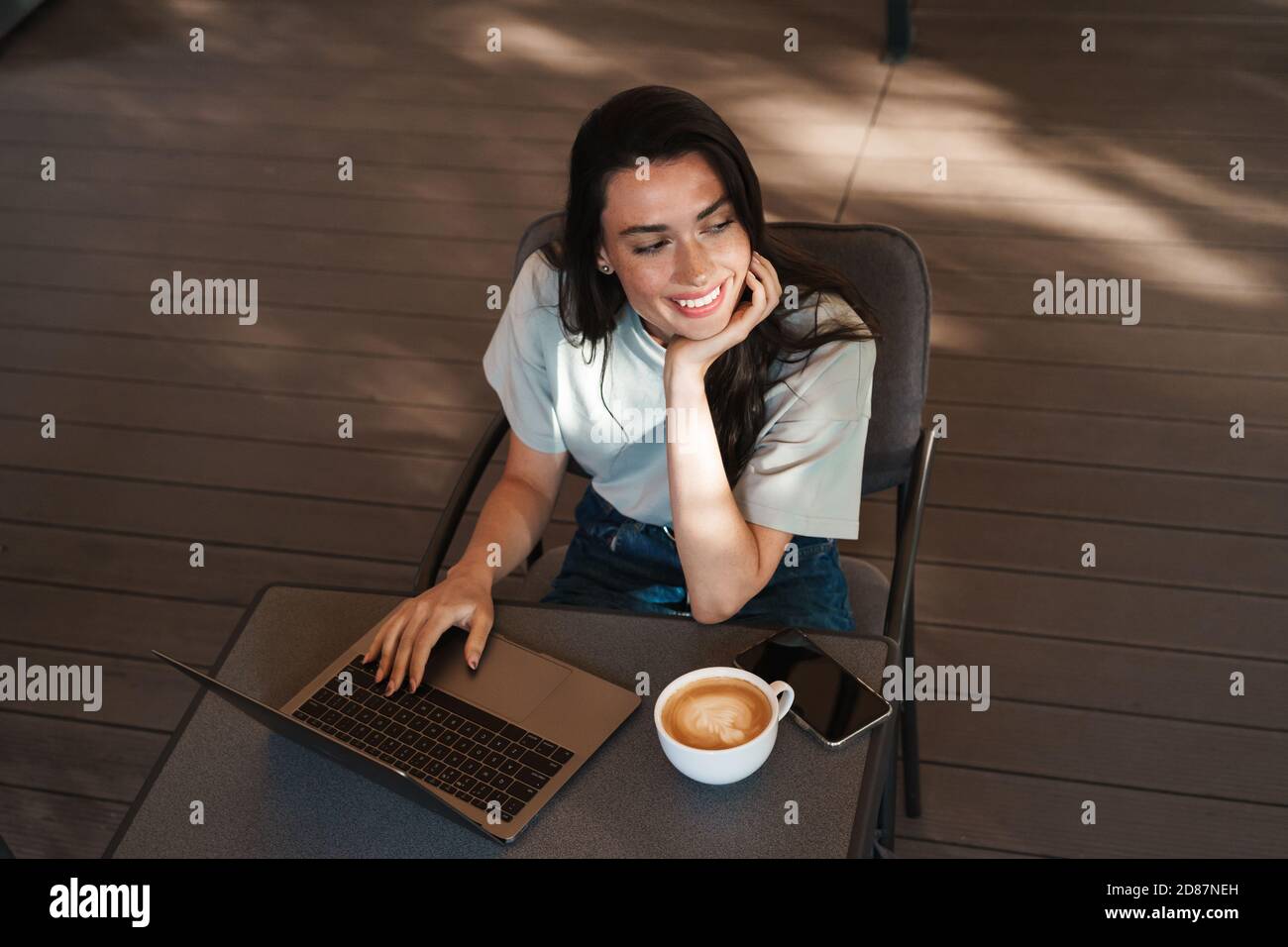 Photo of smiling optimistic pretty young woman sitting in cafe and ...