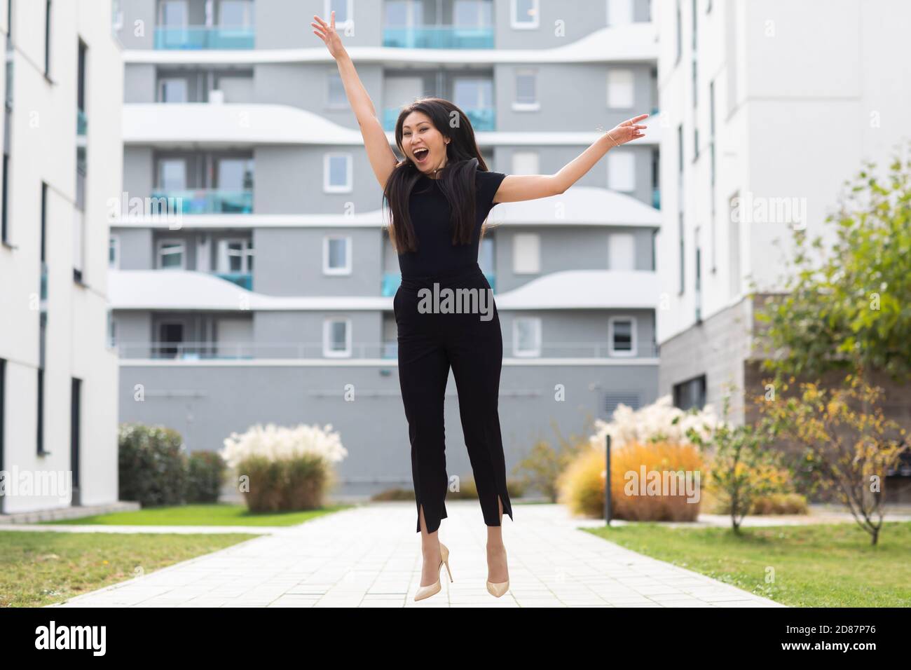 Woman with high heels jumping outside in front of new buildings Stock ...