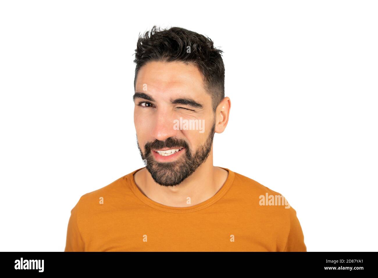 Portrait of young happy man smiling while winking an eye against white ...