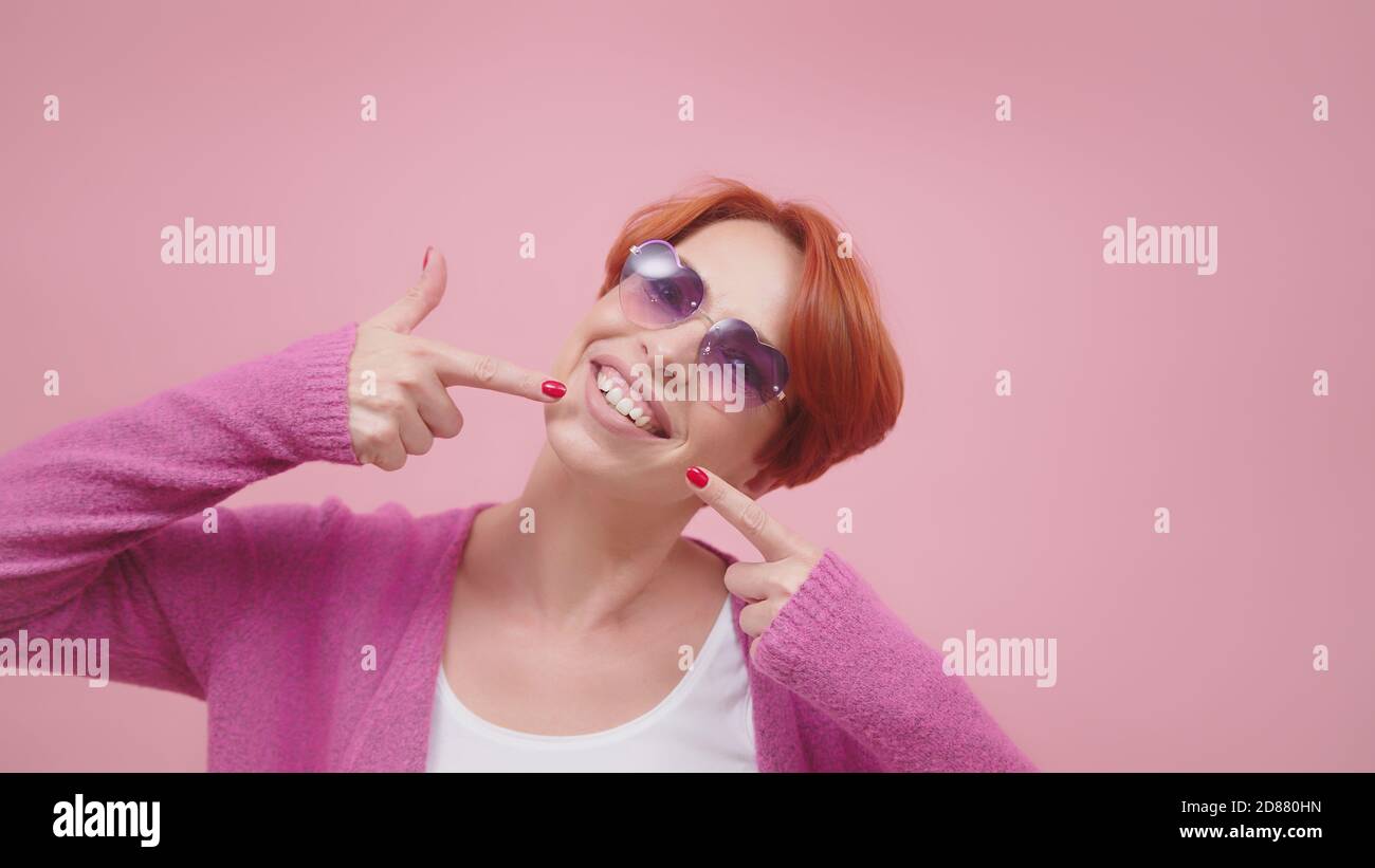 Attractive middle aged woman with red hair pointing fingers on her ...