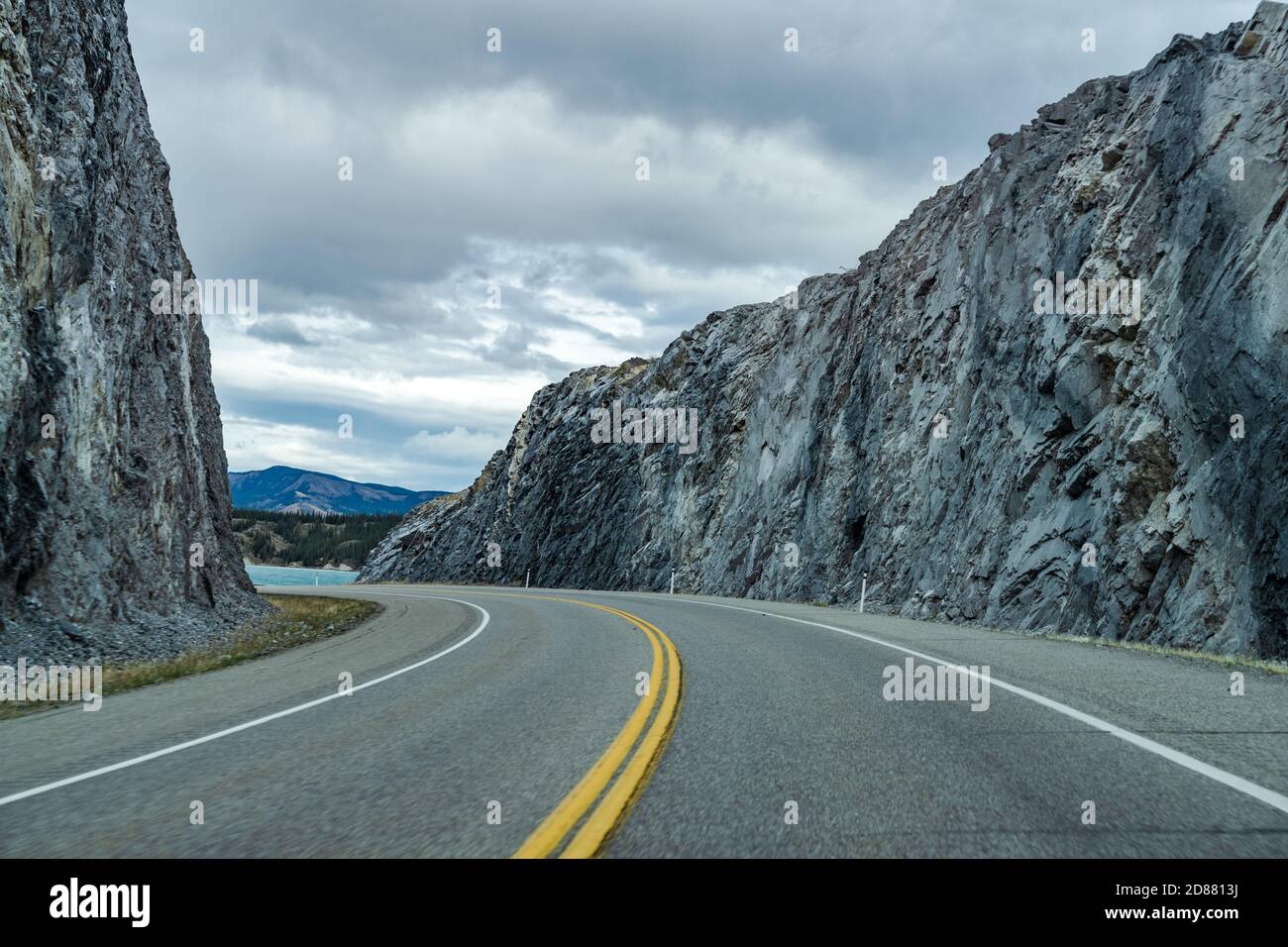 Highway road in the forest, rocks on both sides with mountains in the ...