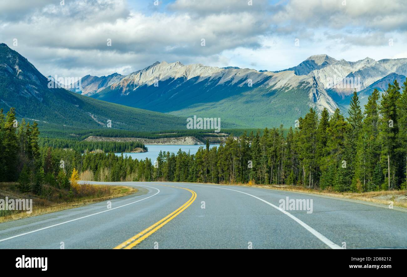 Rural road in the forest with mountains in the background. Alberta ...