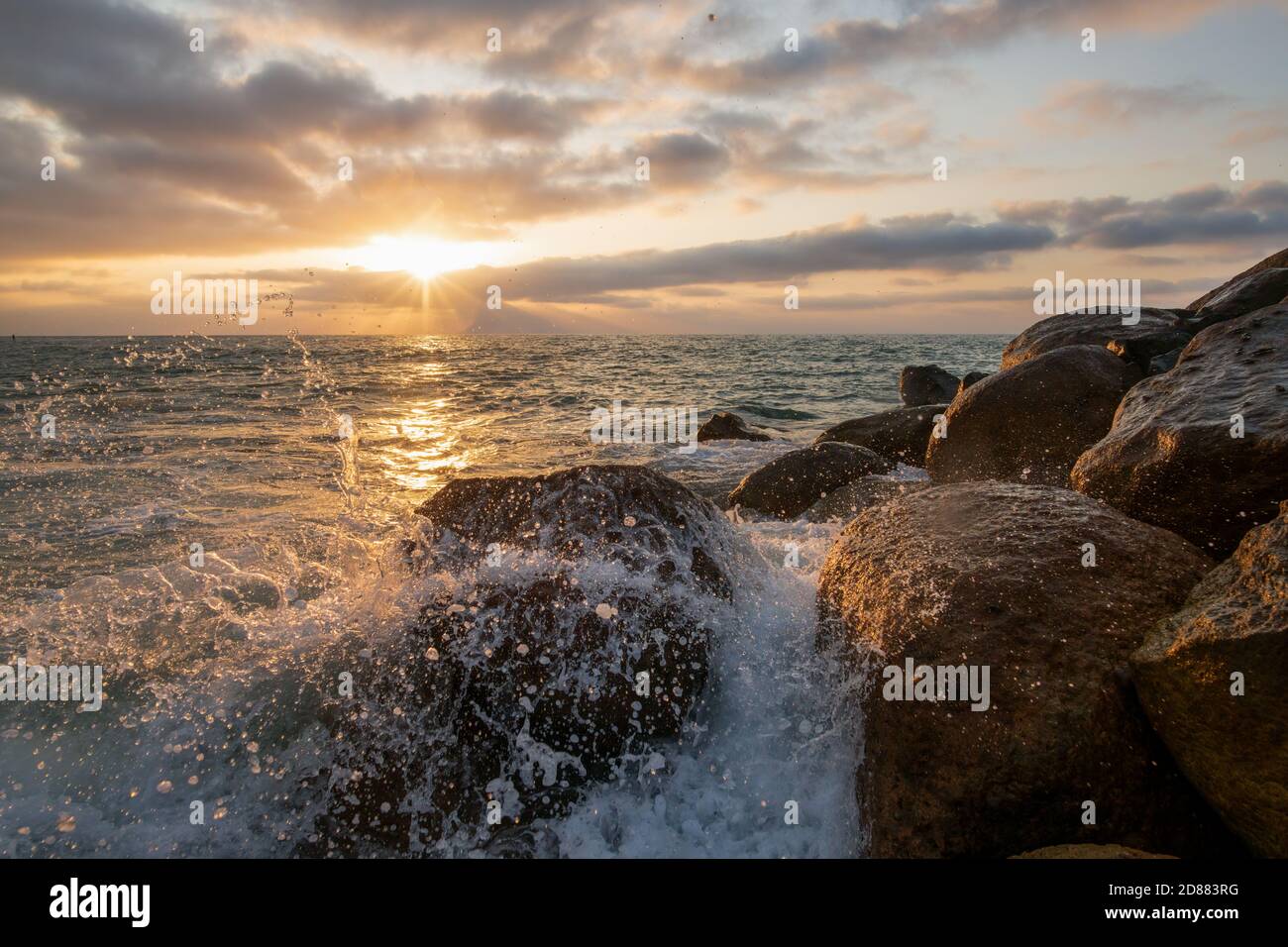 A Sunset Ocean Wave is Breaking on the Sea Shore with the Sun Setting ...