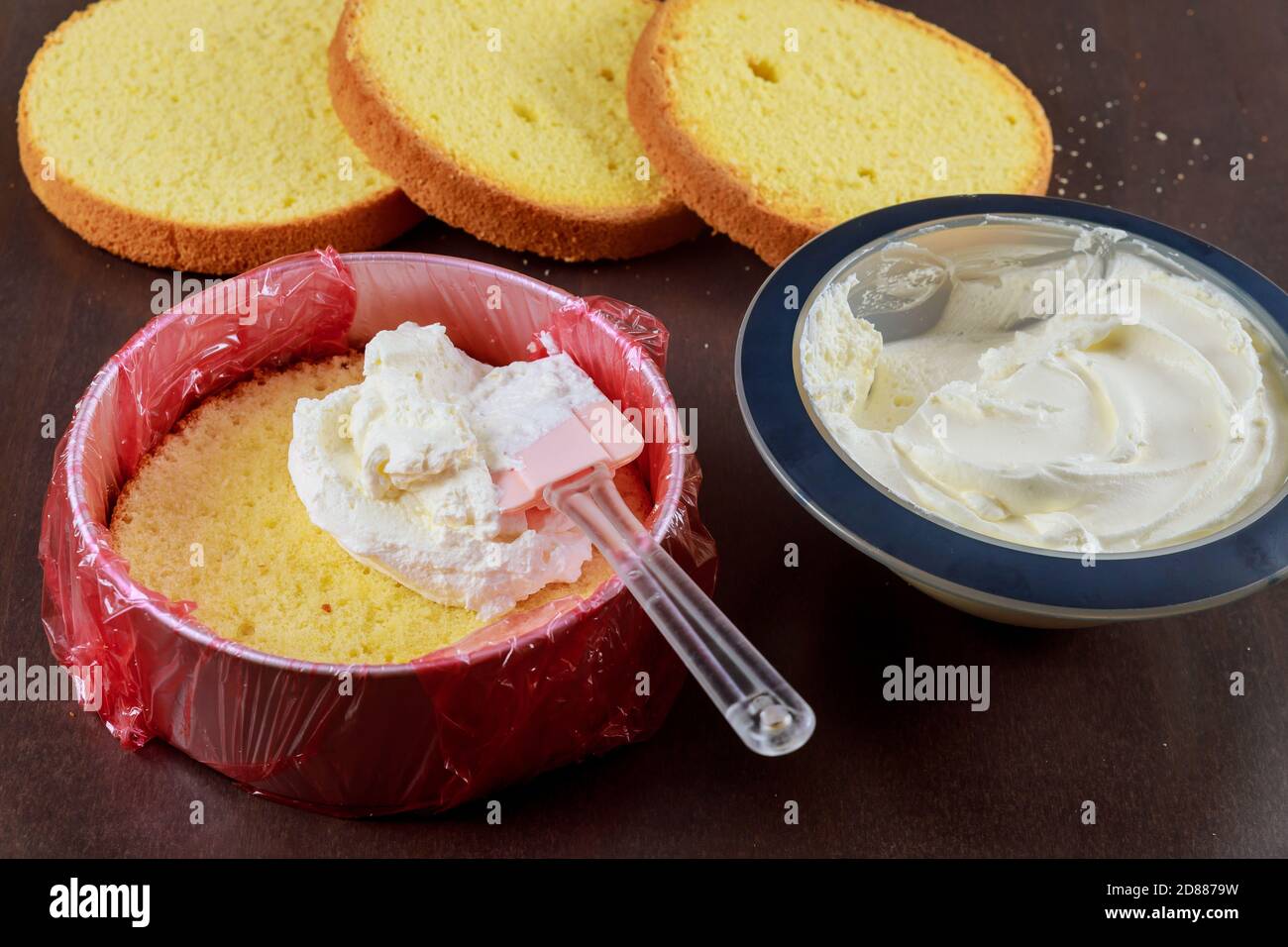 Cake assembly. layer cake with white icing Stock Photo - Alamy