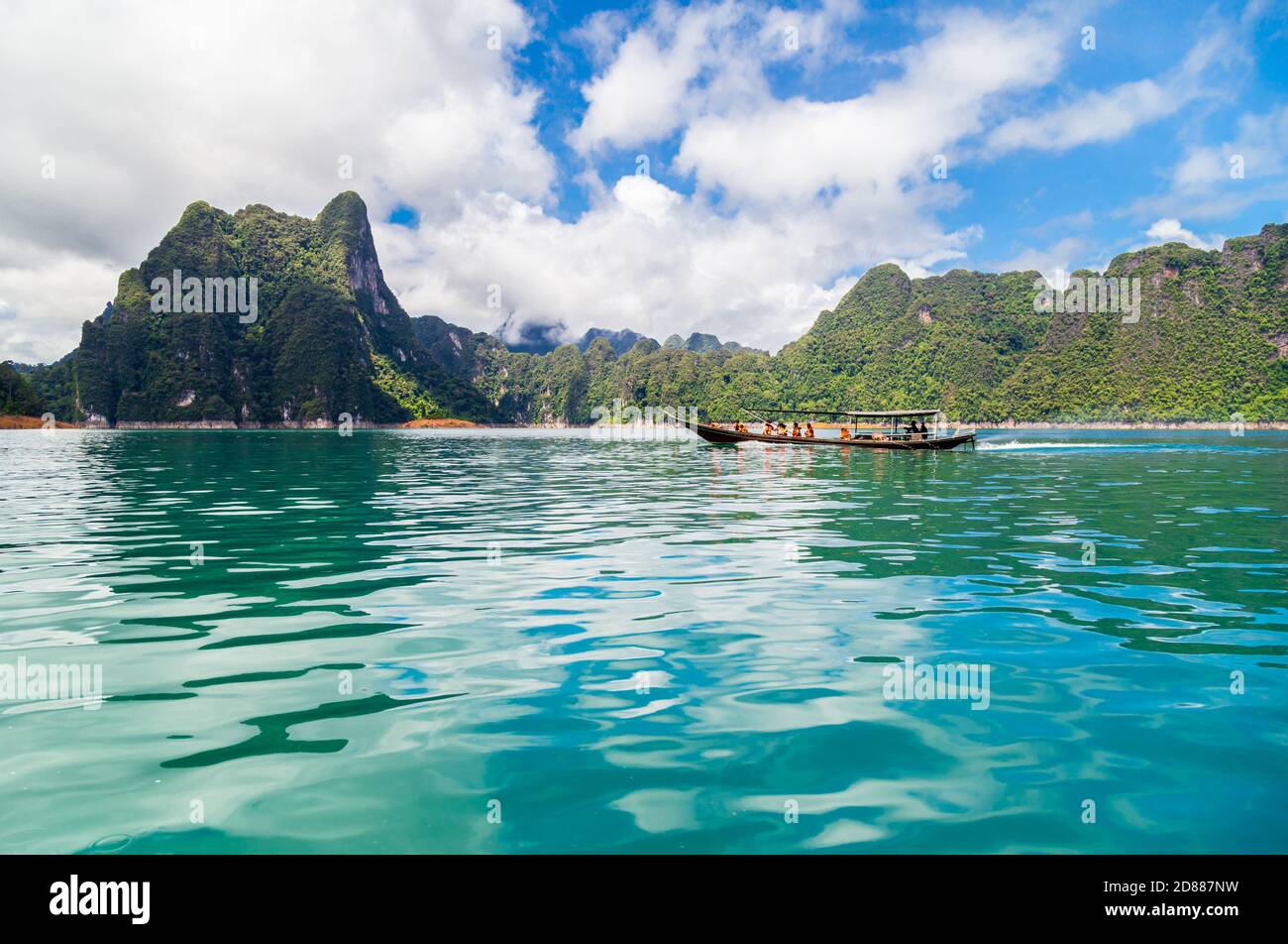 Wooden Thai traditional long-tail boat on a lake with mountains at ...