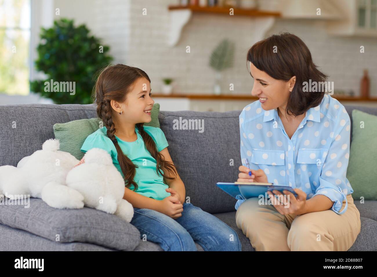 Happy little child communicating with psychologist sitting on sofa ...