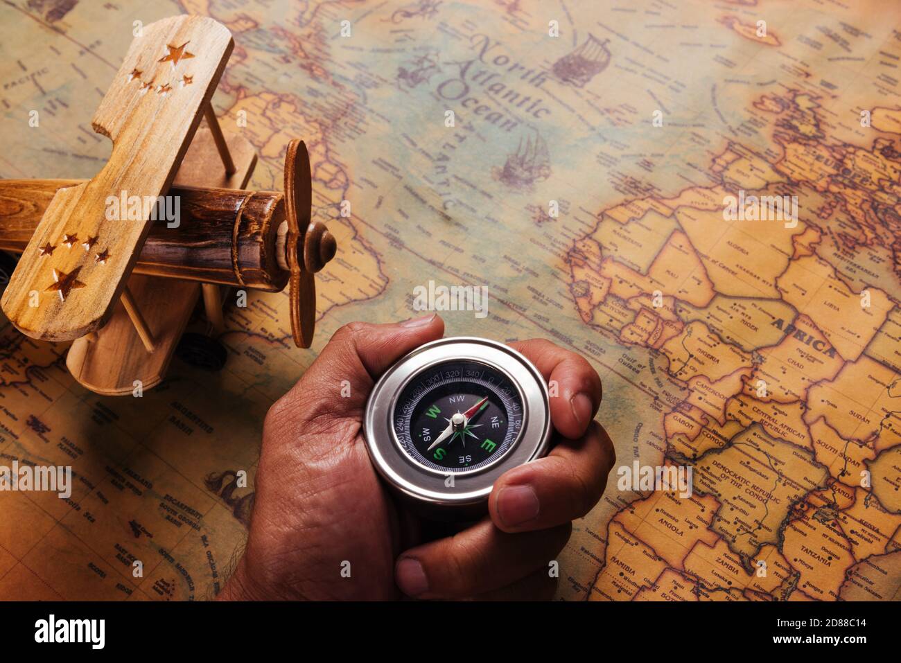 Hand hold old compass discovery and wooden plane on vintage paper ...