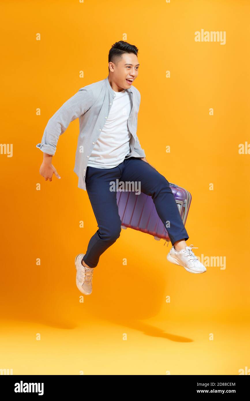 Young creative man is posing with suitcase on yellow background Stock ...