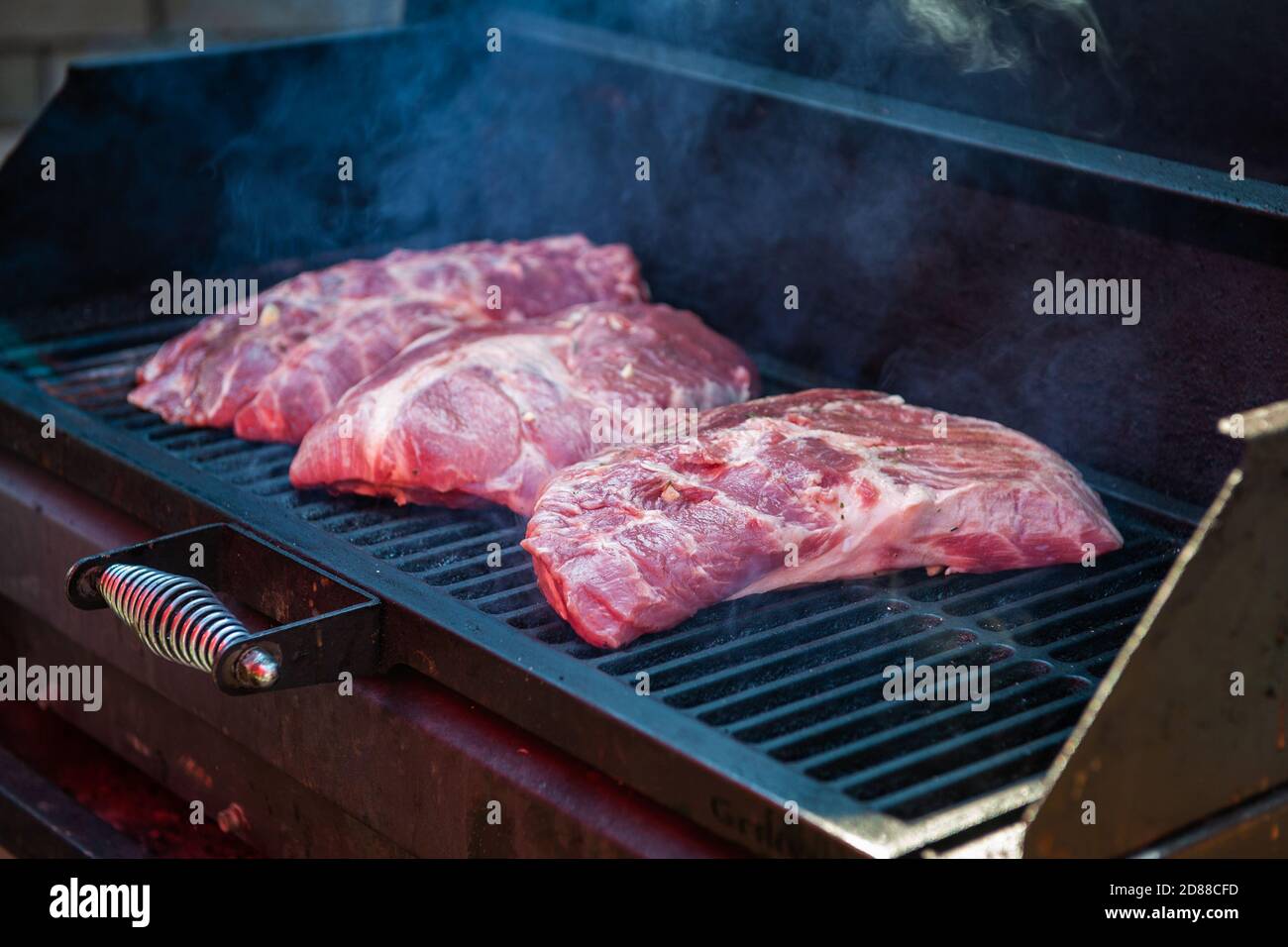 Pork meat steaks on the grill Stock Photo - Alamy
