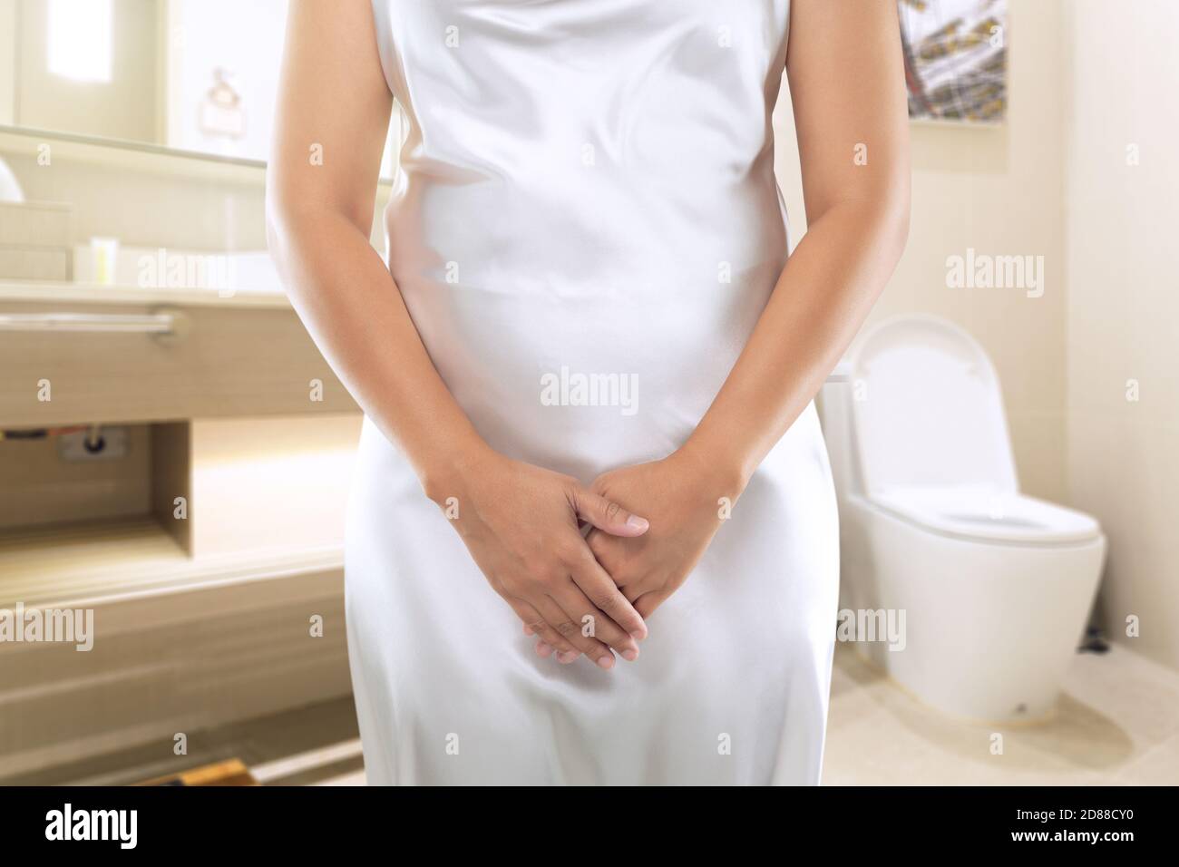 Women in a white dress want to urinating at the toilet. Peeing or ...