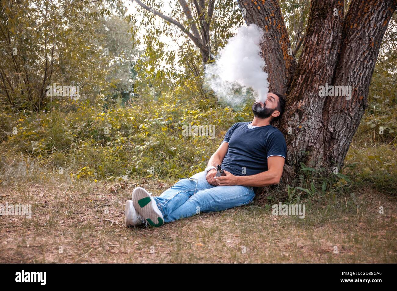 Stylish bearded man blows up a couple an vape. Hybrid cigarette Stock ...