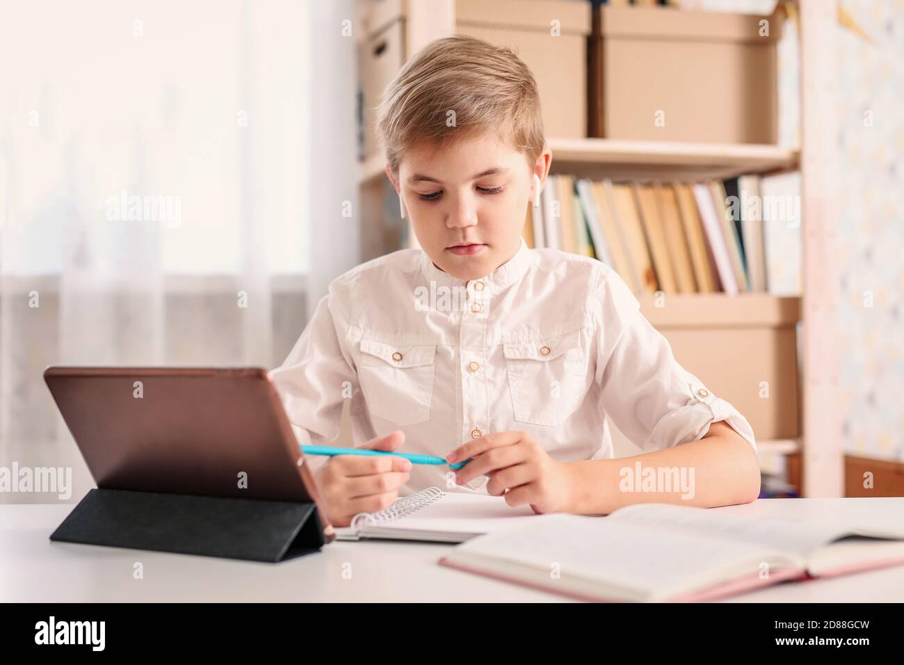 New normal: School boy doing his task at home, using tablet pc and ...