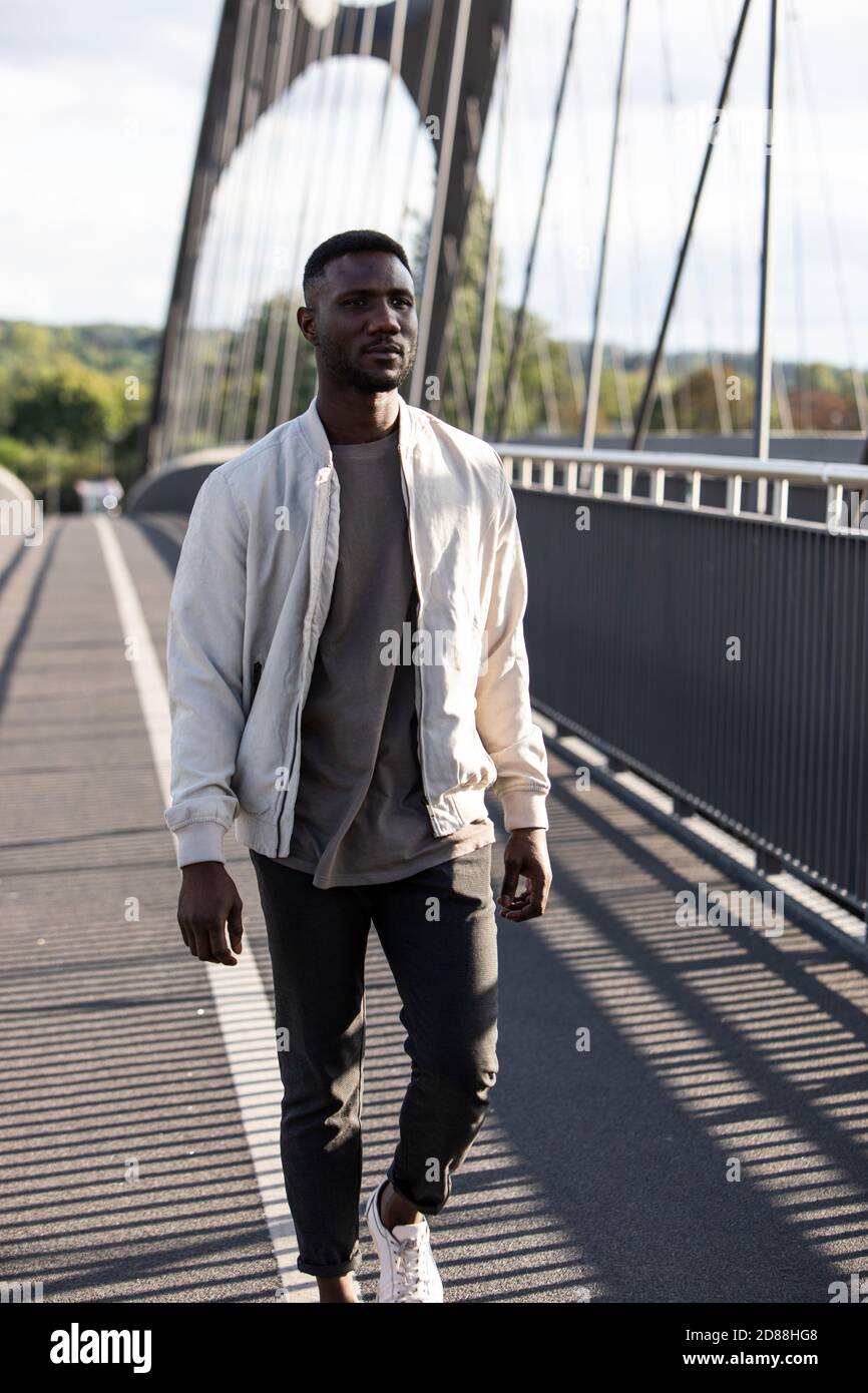 Young black man walking looking away from camera. Three quarter length ...