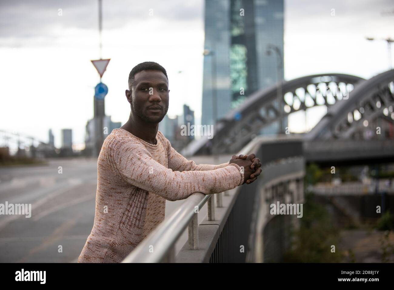 Handsome man standing on bridge leaning arms on railing with head ...
