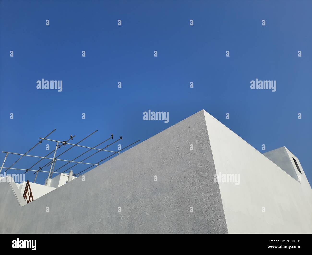 Blue sky over the roof of a white building of a brutalist building ...