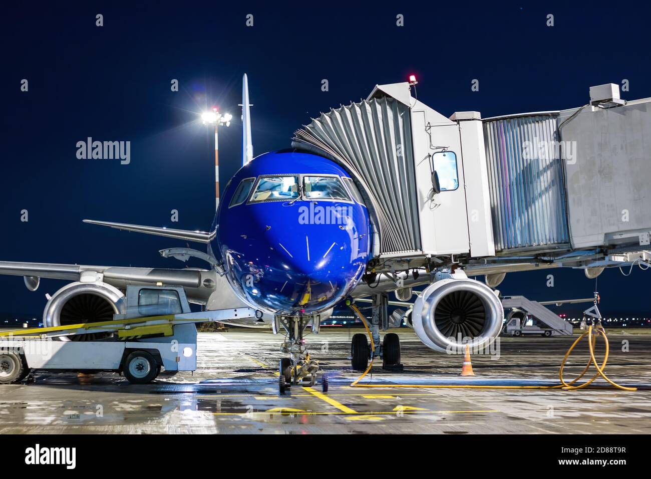 Ground handling of airplane near a passenger ramp at night Stock Photo ...
