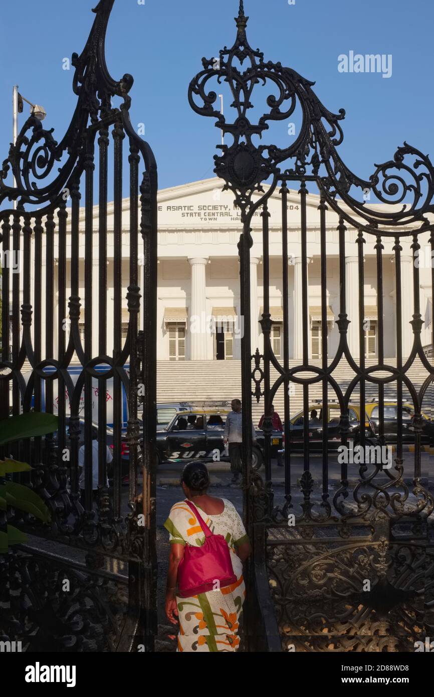 A woman passes through a wrought iron gate of Horniman Circle Garden; b ...