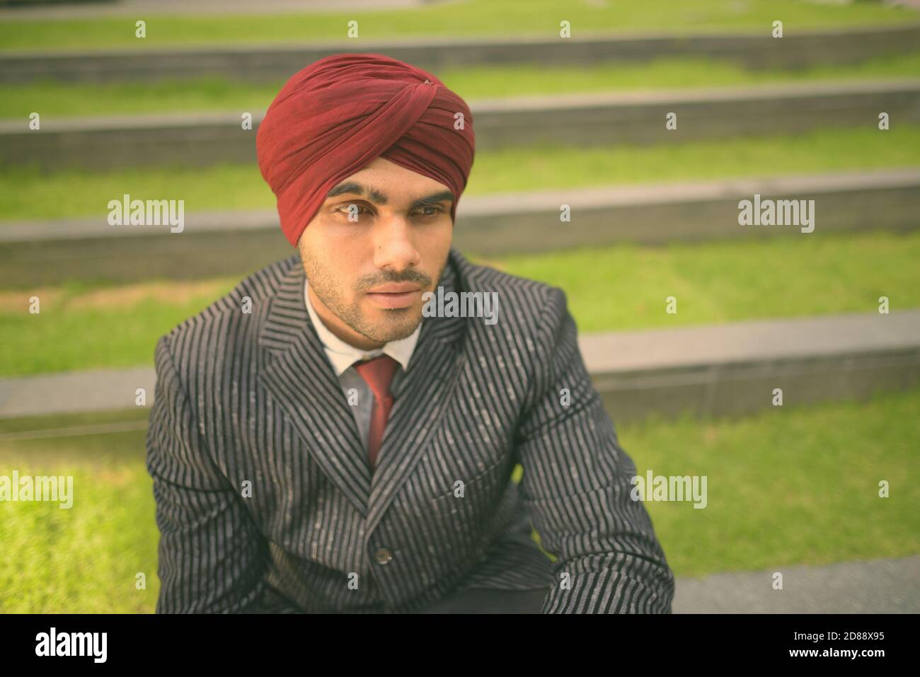 Young handsome Indian Sikh businessman wearing turban while exploring ...